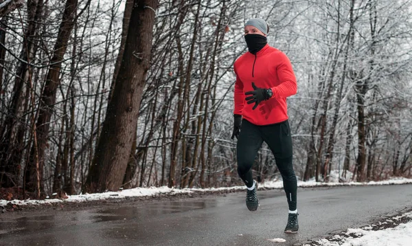 Winter running exercise, runner on road in snowy forest - Stock Image ...
