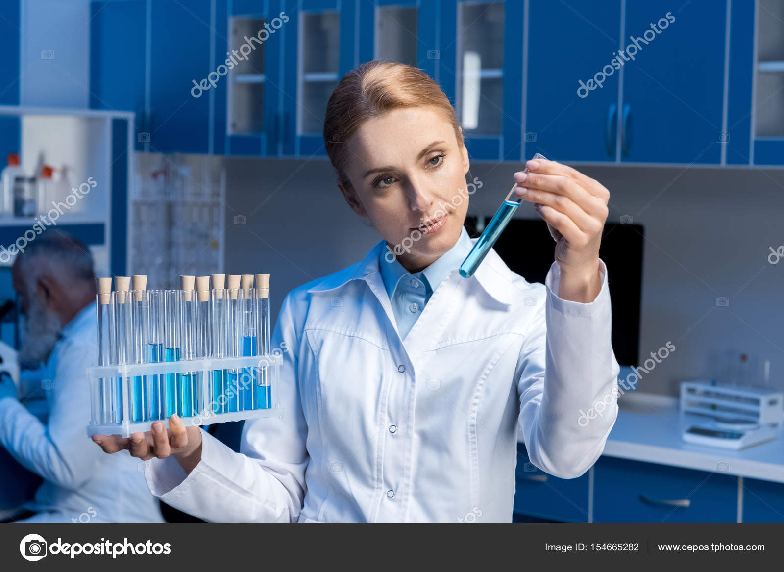 Scientist in lab coat looking at tube — Stock Photo © DimaBaranow ...