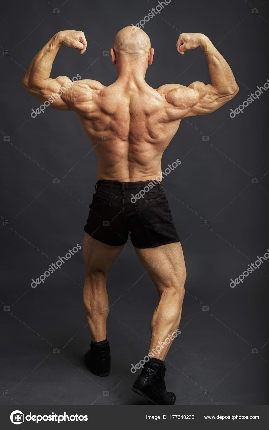 Athlete in back double biceps pose. Bodybuilder showing muscles on studio background Stock Photo ...