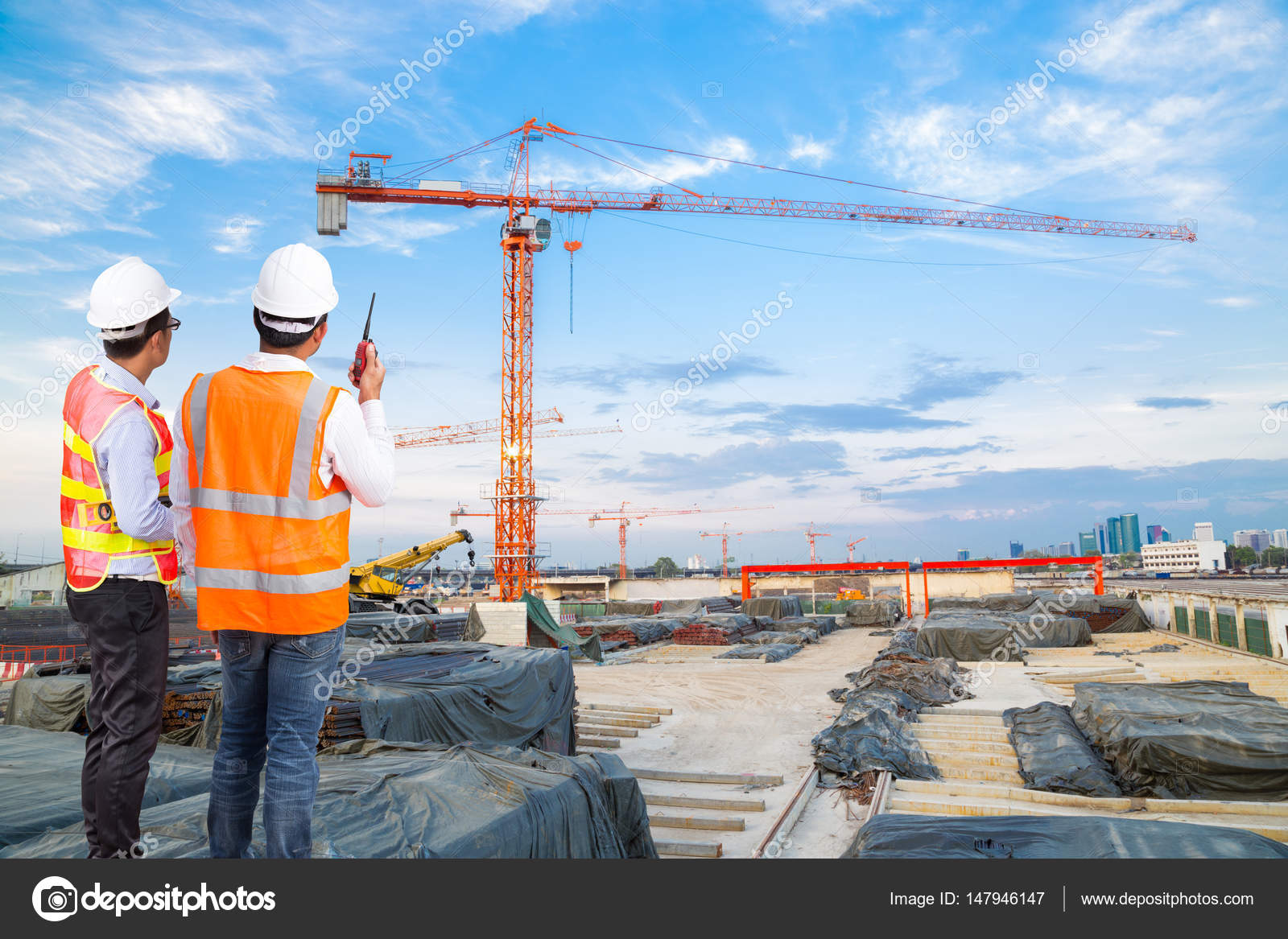 Engineer and foreman looking at crane construction with talking on the ...