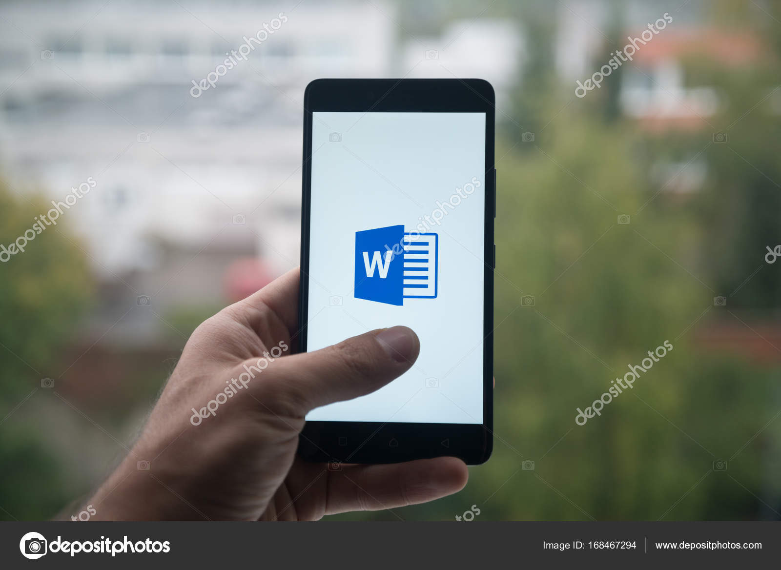 Man holding smartphone with Microsoft Office word logo with the finger ...