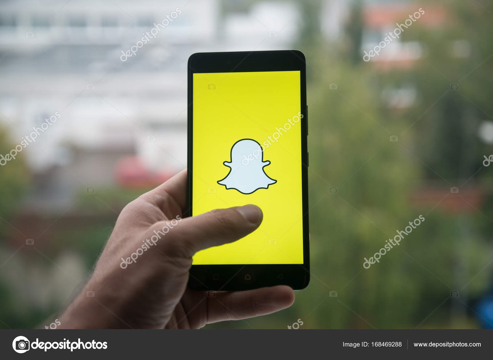 Man holding smartphone with Snapchat logo with the finger on the screen ...