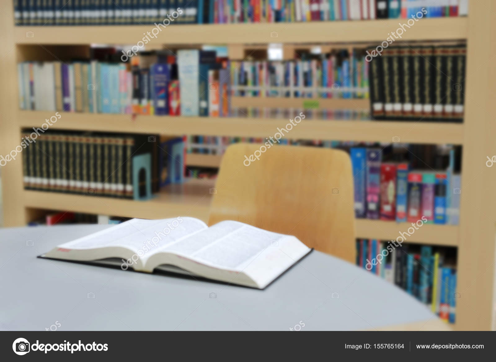 Blurred library with open book on table desk and bookshelf, abstract ...