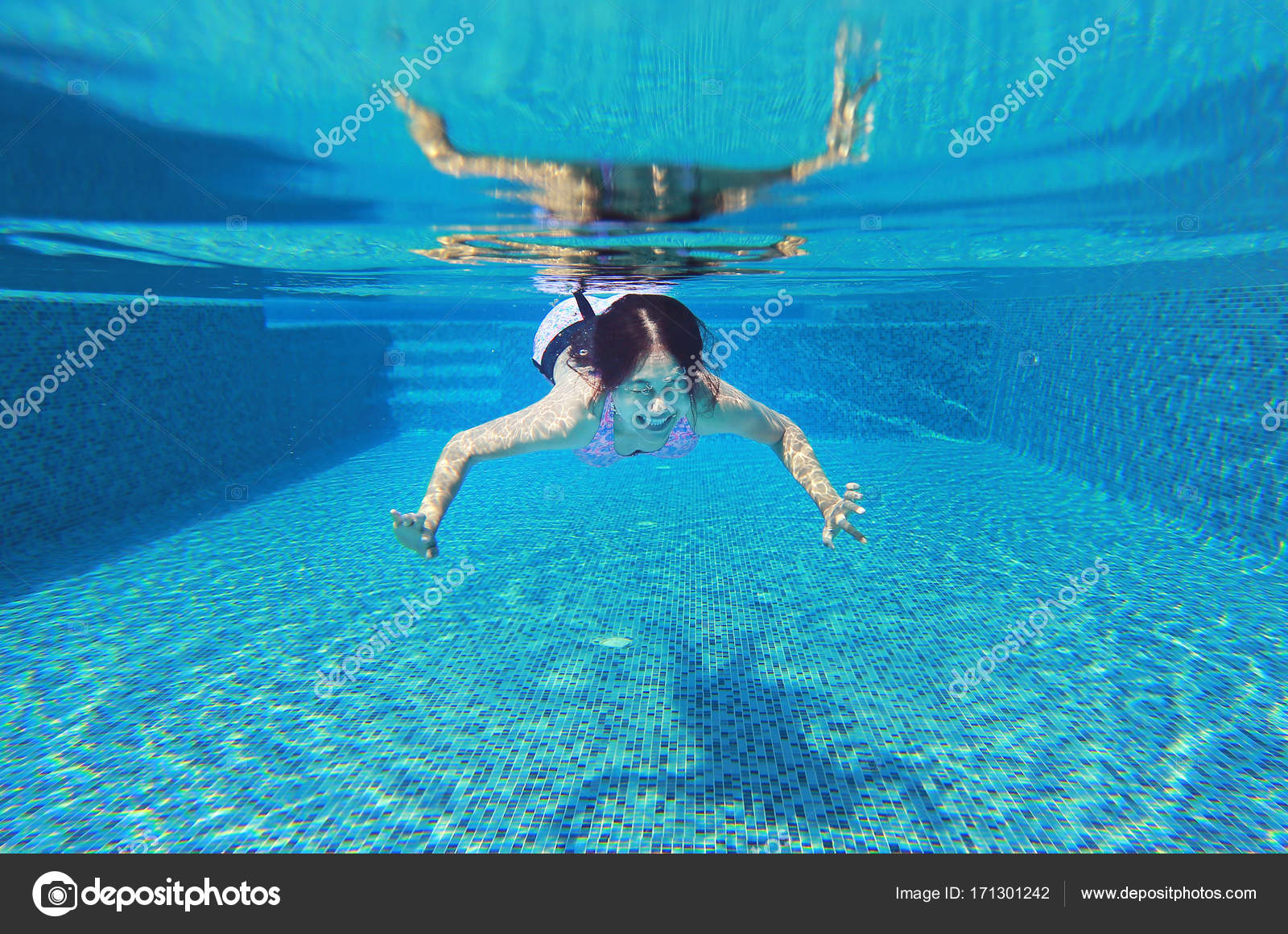 Underwater Shot Of Young Woman Diving Into The Swimming Pool Stock