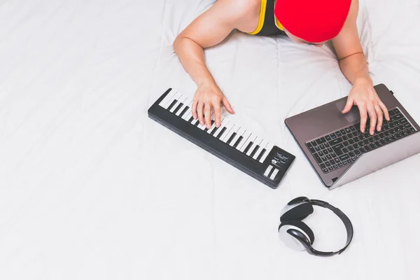 asian male artist composing a song on computer laptop, wireless midi ...
