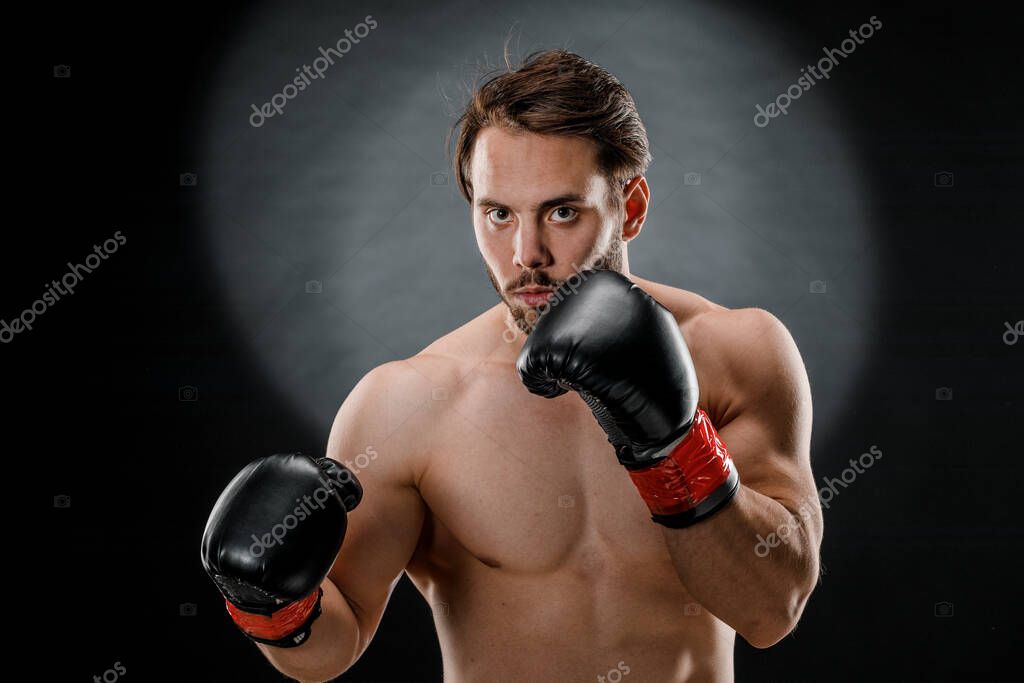 Un hombre con guantes de boxeo. Un hombre boxeando sobre un fondo negro ...