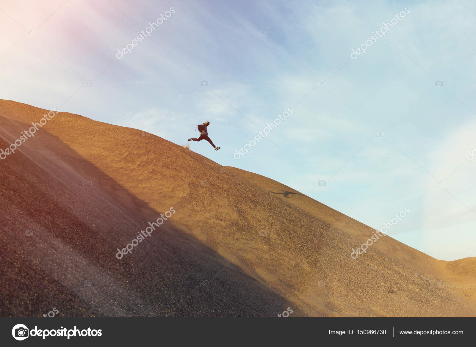 Brave man with backpack running and jumping on a dune in the desert ...