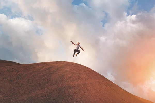 Crazy and brave man athlete jumps on dunes and hills in desert. Deft ...