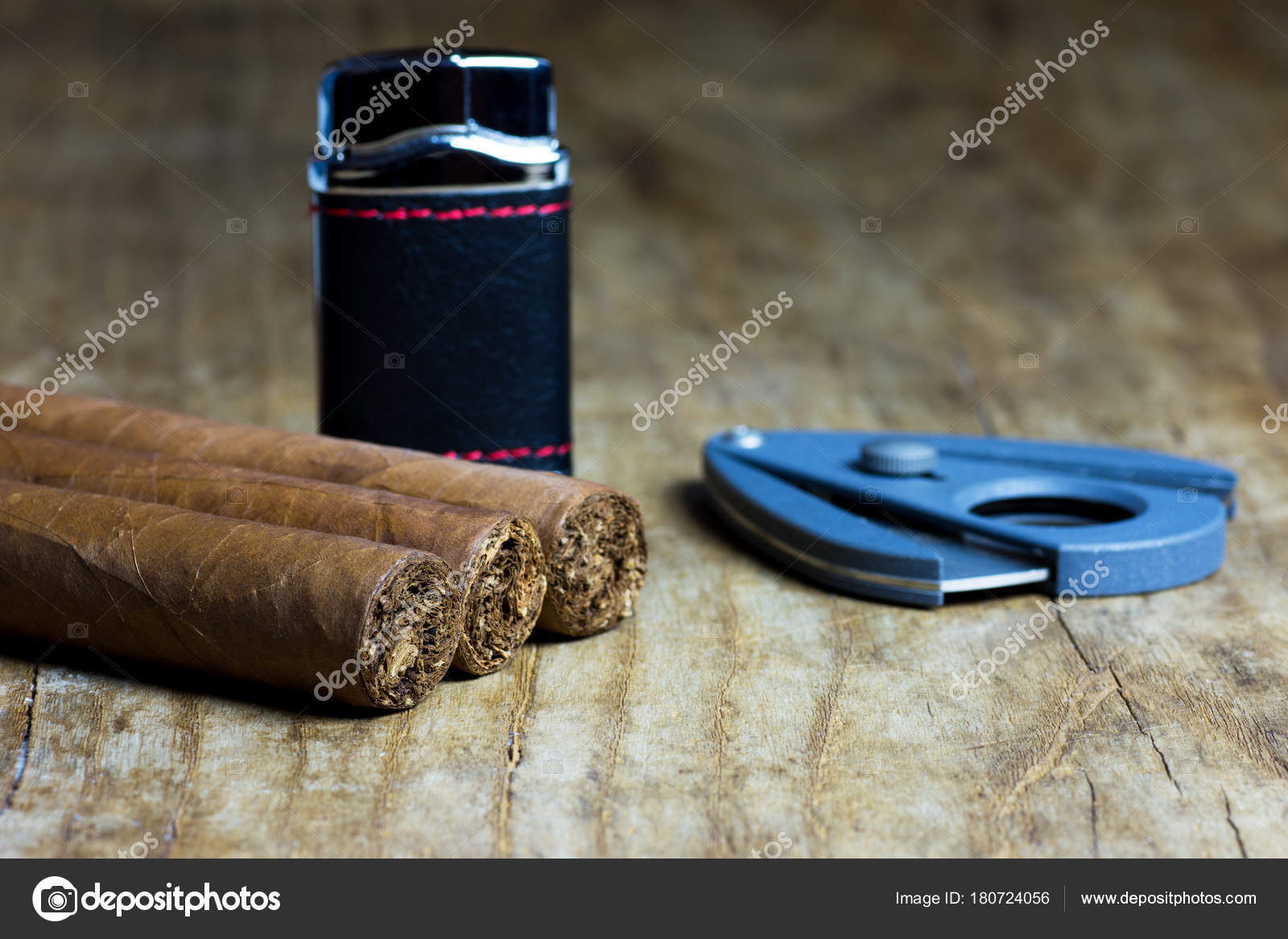 Three Cuban cigars with a lighter and a cutter on an old wooden board ...