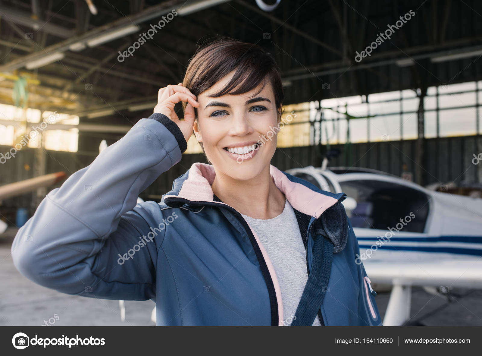 Female pilot posing in hangar Stock Photo by ©stokkete 164110660