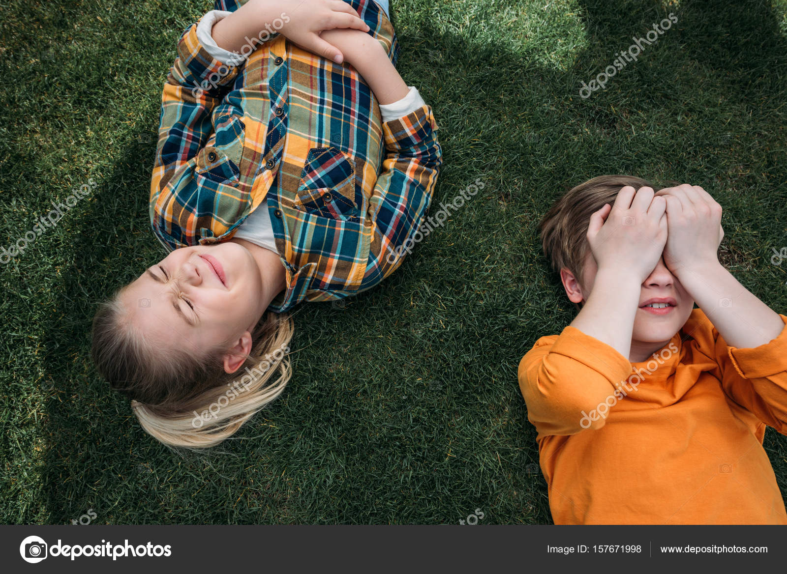 Adorable kids sunbathing while lying on grass Stock Photo by ...