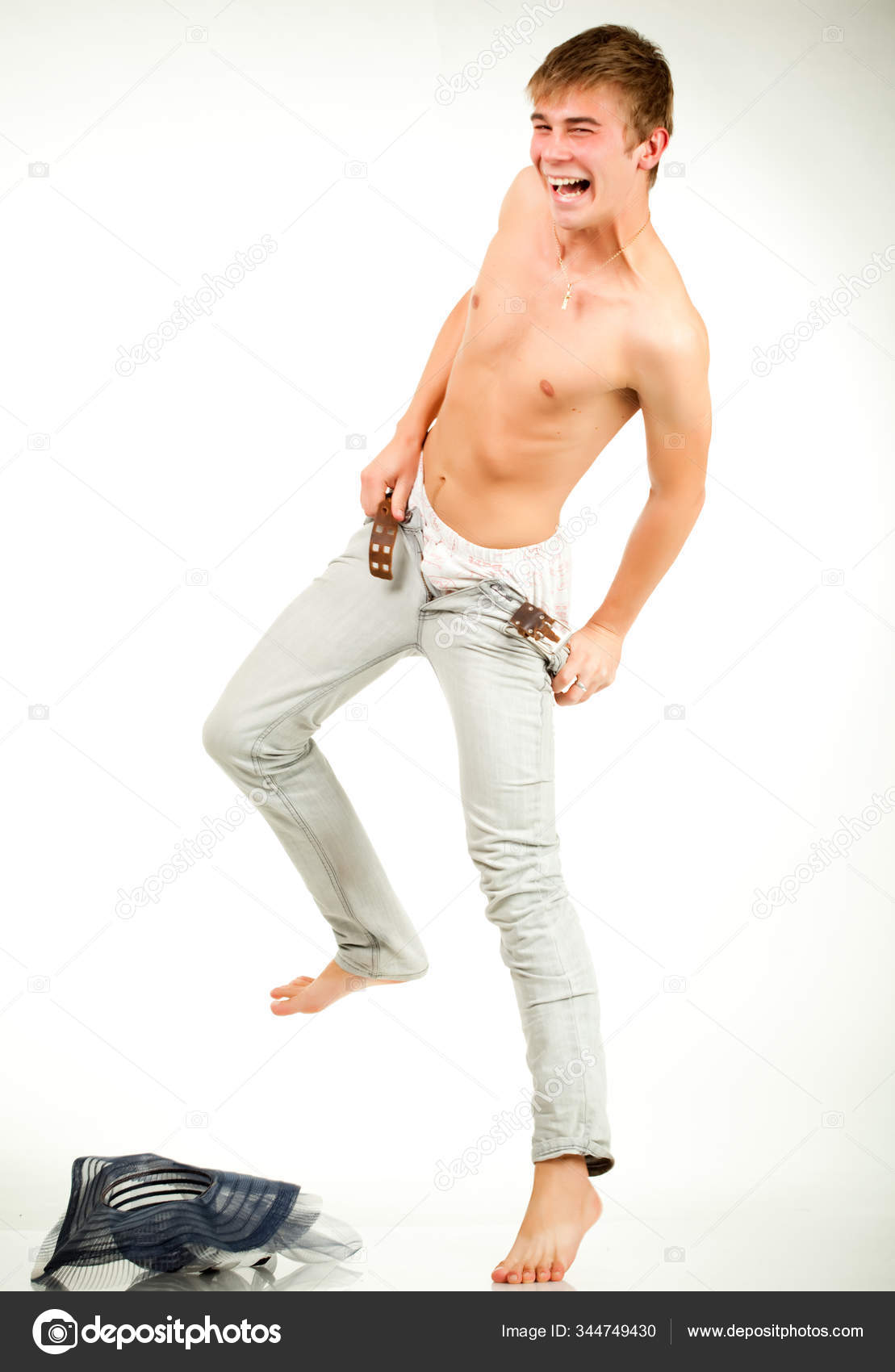 Intimate fun portrait of a young fit man putting his pants on with ...