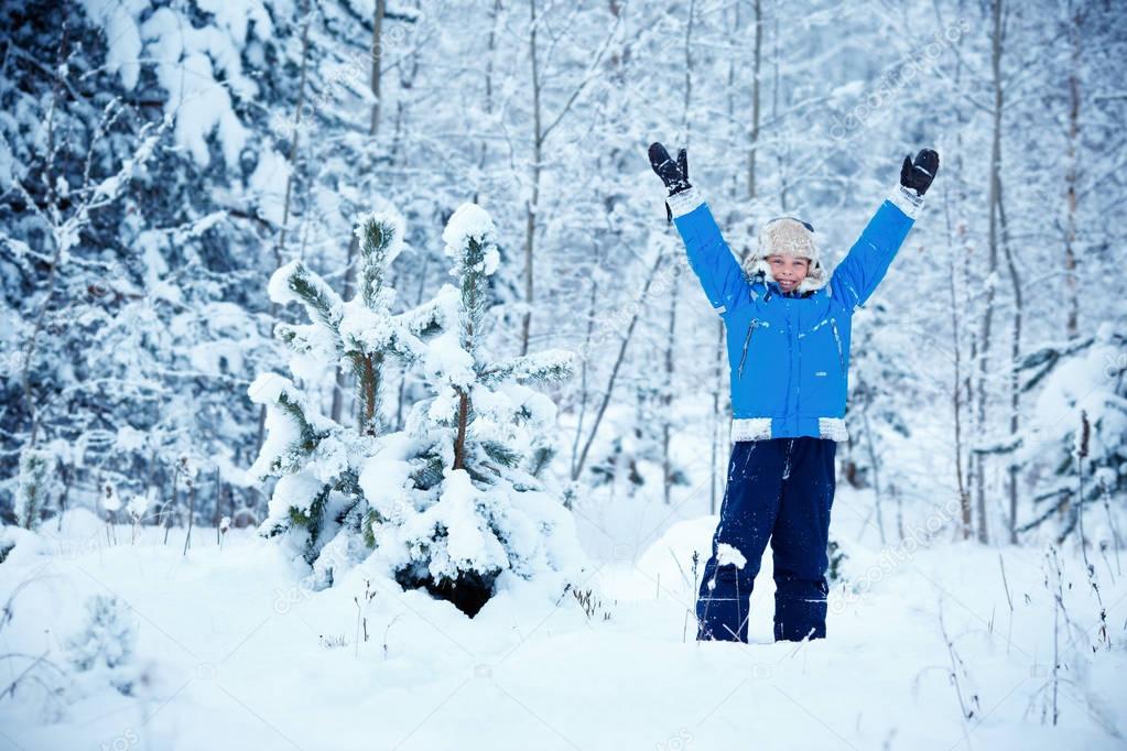 Милый маленький мальчик в теплой одежде играет в зимнем лесу в ...