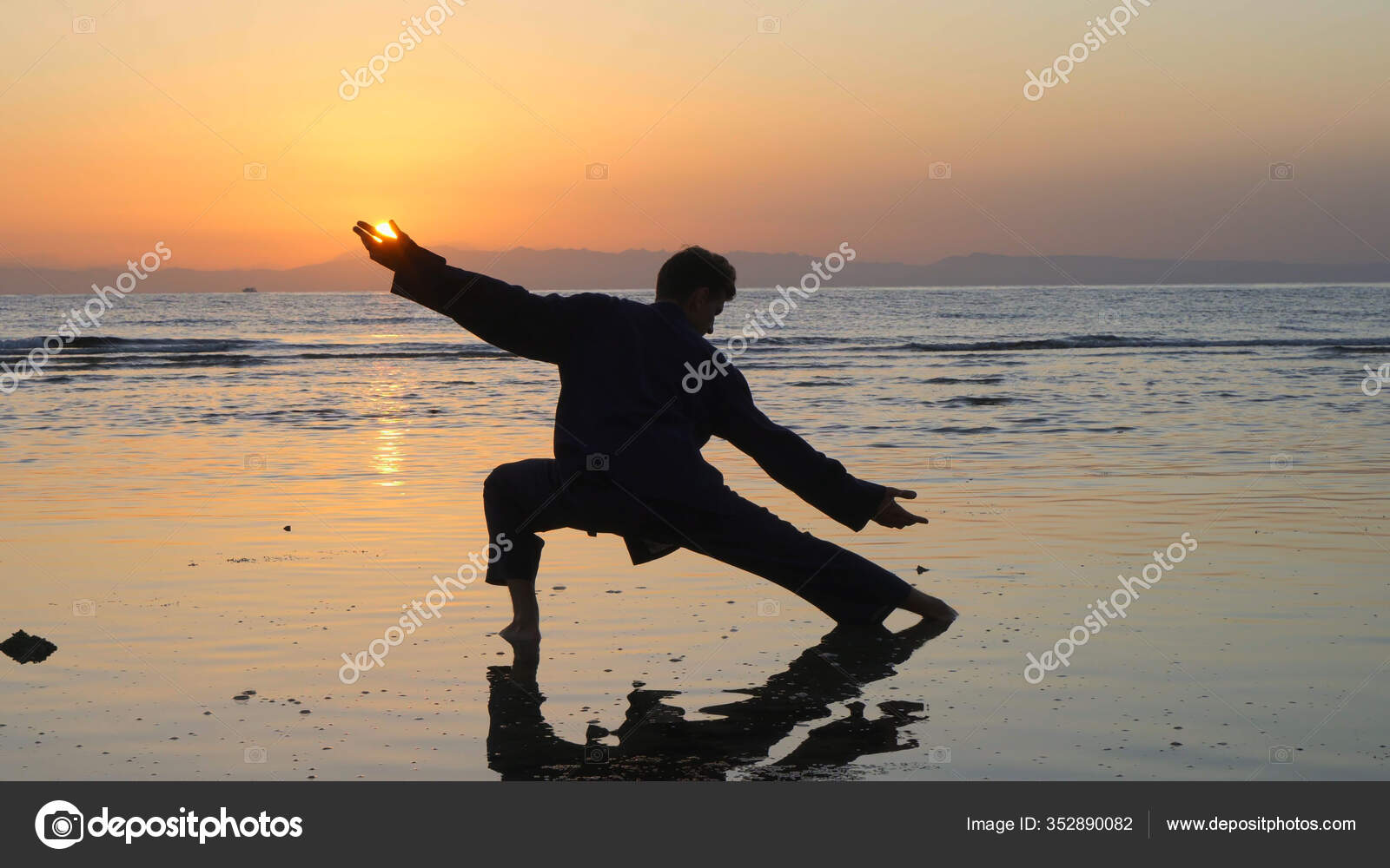 Silhouette of man practicing energy exercises at sunset by the sea ...