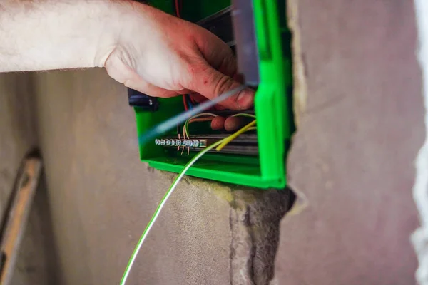 Hands electrical wiring is pulled through the hole in the wall of the ...