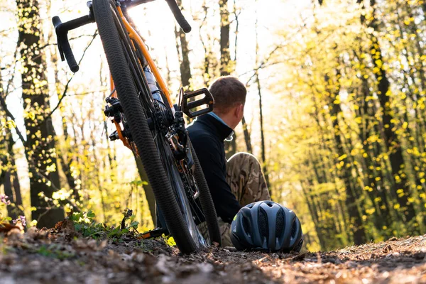 a tired guy sits on a forest path, rests and looks at a bicycle - Stock ...