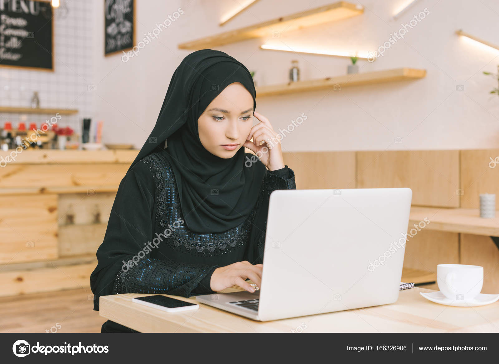 Muslim woman using laptop in cafe — Stock Photo © IgorVetushko #166326906