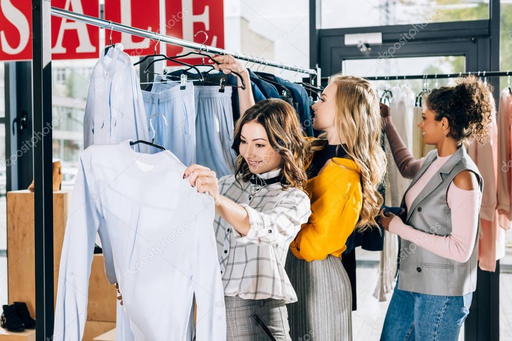grupo de mujeres felices en las compras en la tienda de ropa el día de ...