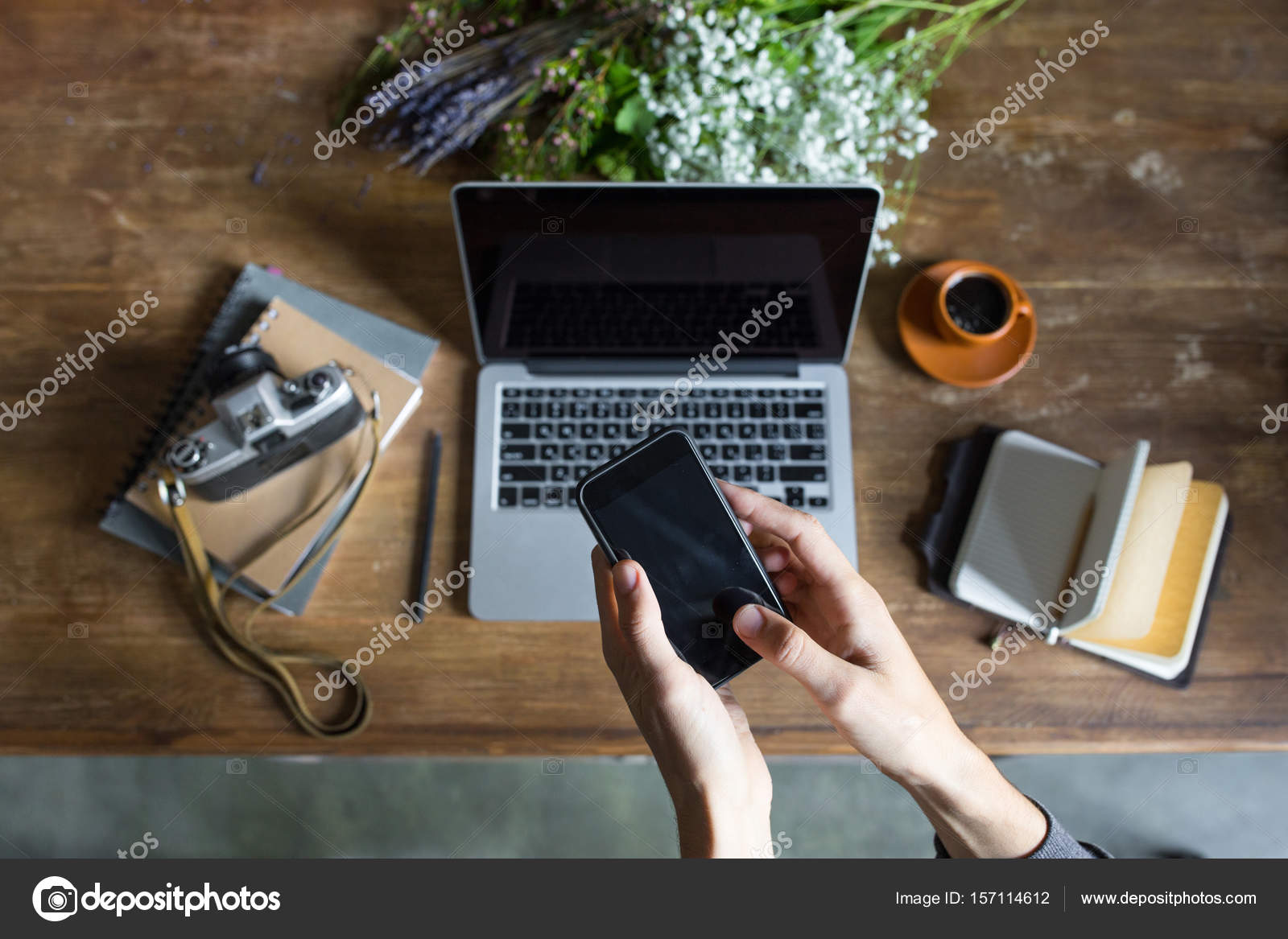 Person using smartphone and laptop at workspace with notebooks and ...