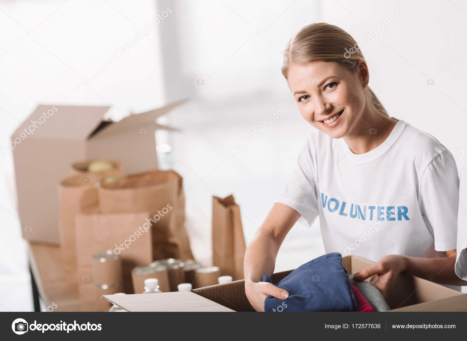 Female volunteer putting clothes into box — Stock Photo © AllaSerebrina ...