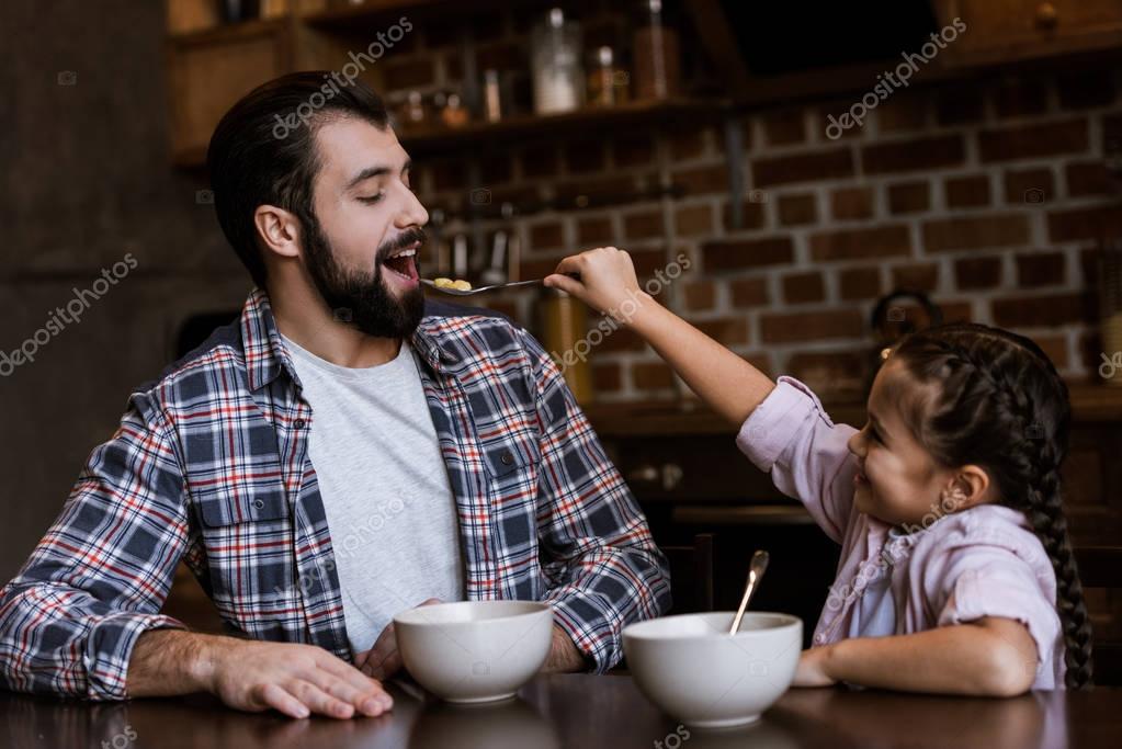 alegre familia en la mesa, hija alimentación padre por bocadillos con ...