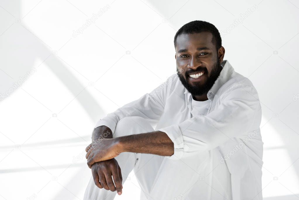sonriente guapo africano americano hombre en blanco ropa sentado y ...
