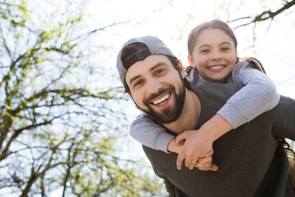 portrait of smiling daughter on father back in park - Stock Image ...