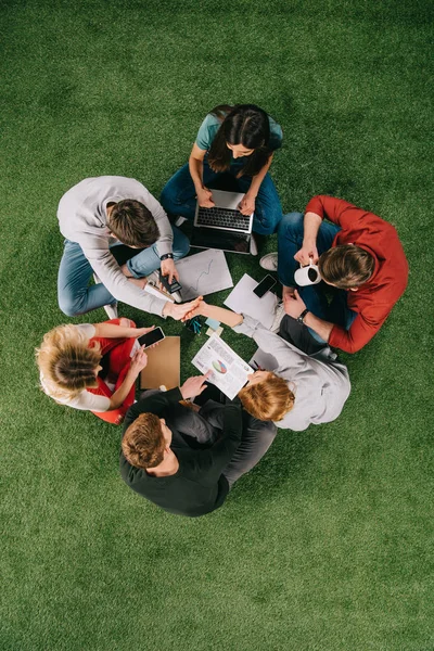 overhead view of two business colleagues shaking hands while other ...