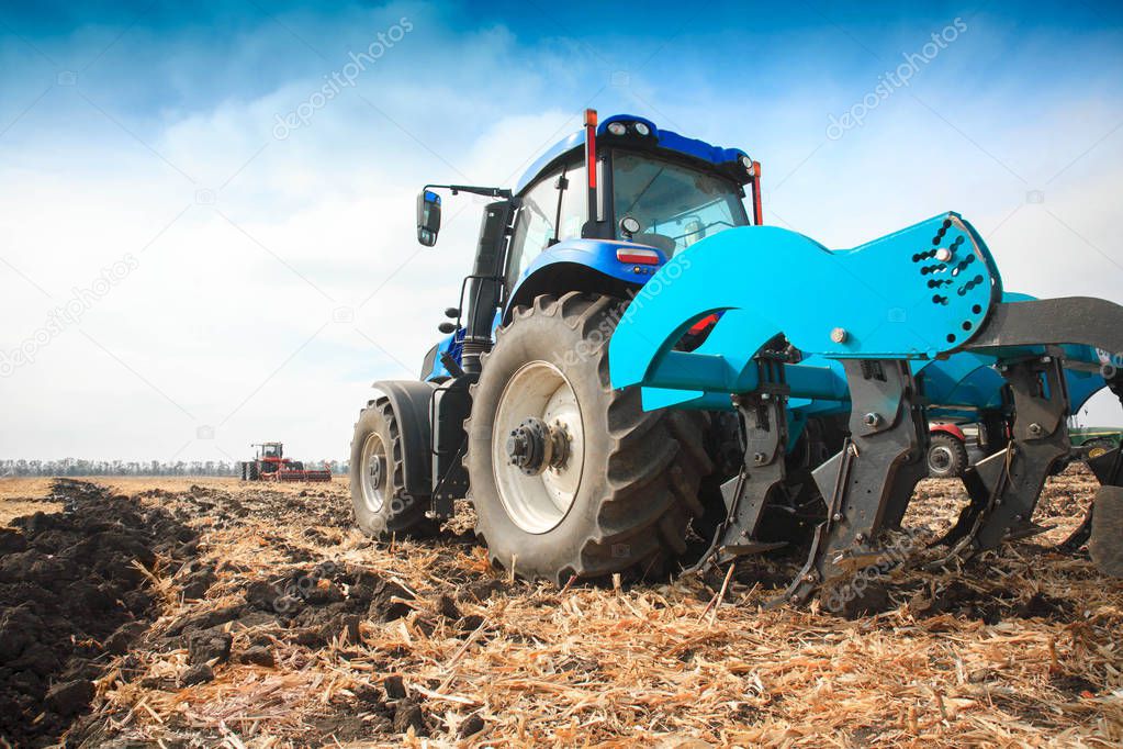 Un tractor moderno con un arado arrastrado en el campo en un día ...
