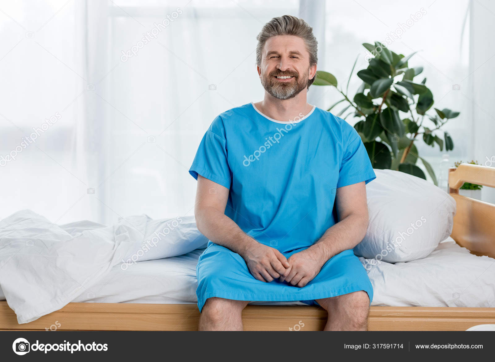 Uśmiechnięty Pacjent Sukni Medycznej Siedzący Łóżku Patrzący Kamerę ...