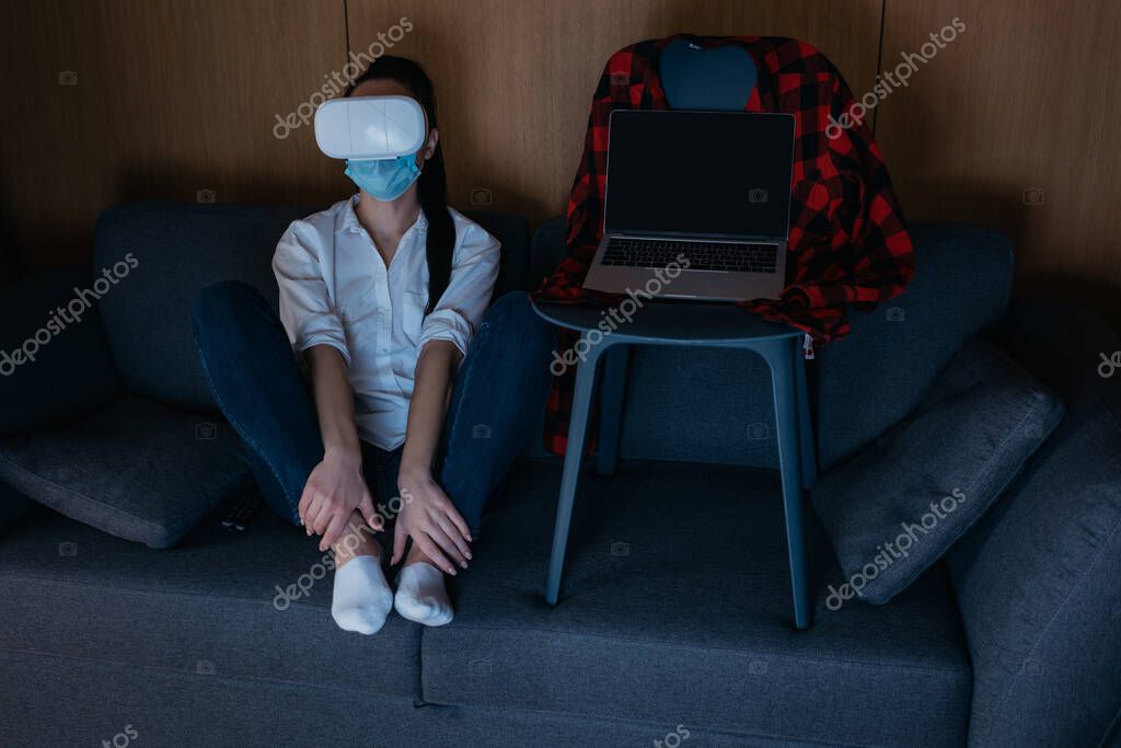 mujer deprimida sentada en el sof y usando auriculares vr cerca de la computadora port til con ...