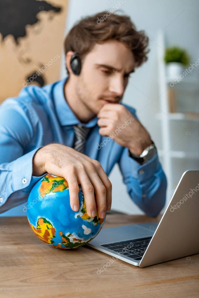 enfoque selectivo de agente de viajes reflexivo tocar globo mientras ...