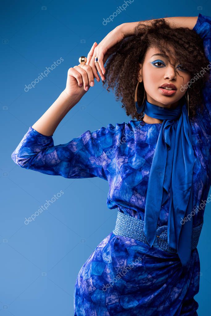 mujer afroamericana con estilo en vestido mirando a la cámara aislada en azul 2024
