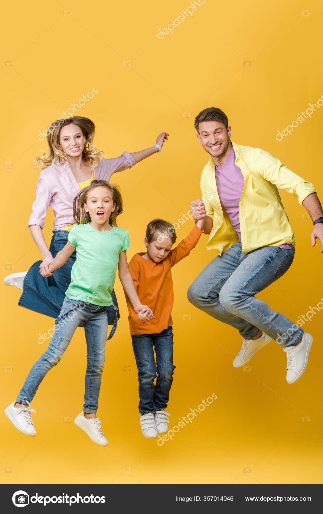 Excited Family Jumping Holding Hands Yellow Stock Photo by ...