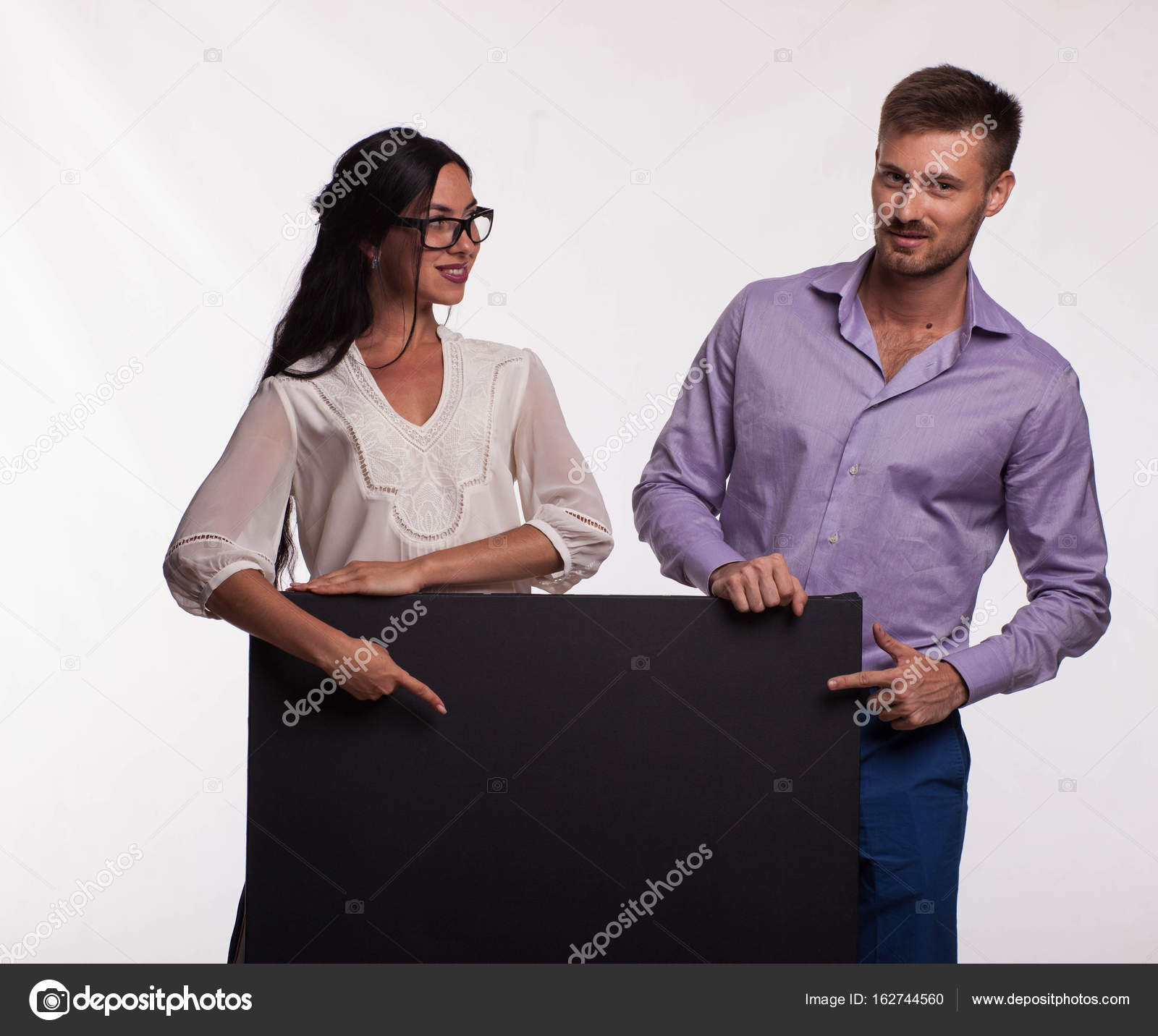 Young confident couple showing presentation pointing placard — Stock ...