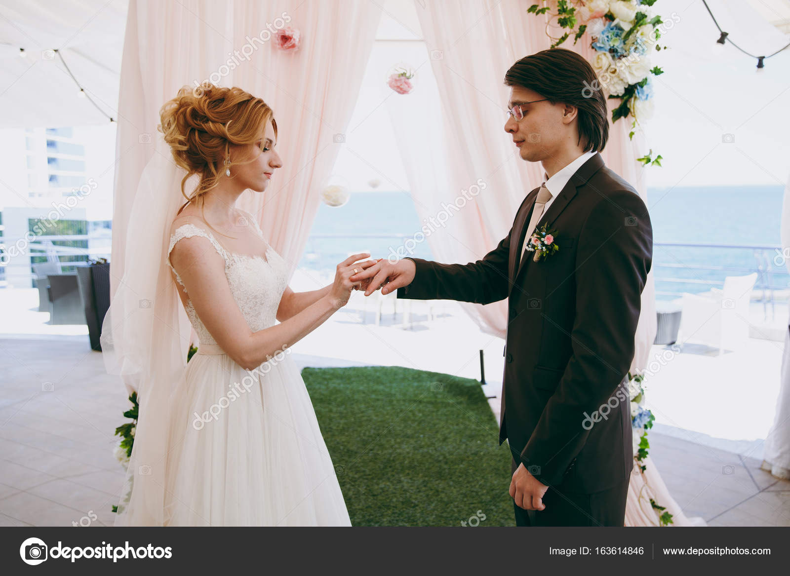 Bride and groom put rings on each other and show them at the ceremony ...