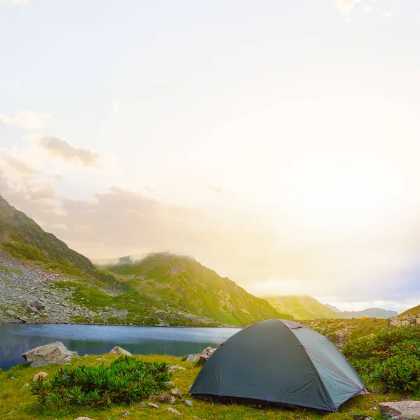 touristic camp near a small lake in a mountain valley at the sunset ...