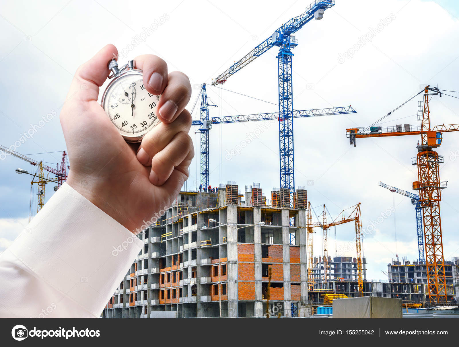 Buildings with cranes and stopwatch in male hand — Stock Photo © Garsya ...