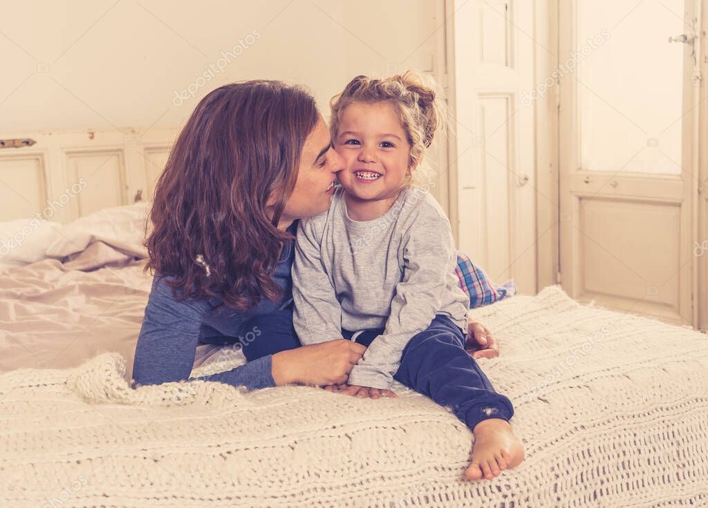 Retrato de estilo de vida de la hermosa madre y su hija relajándose en la cama. Mamá y linda ...