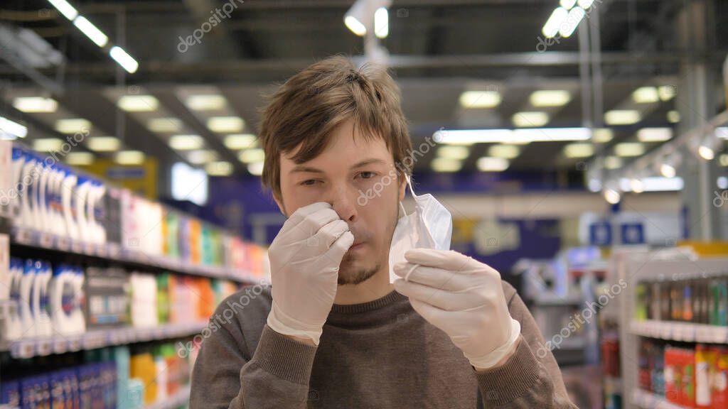 El hombre con una máscara médica y guantes de goma en un supermercado ...