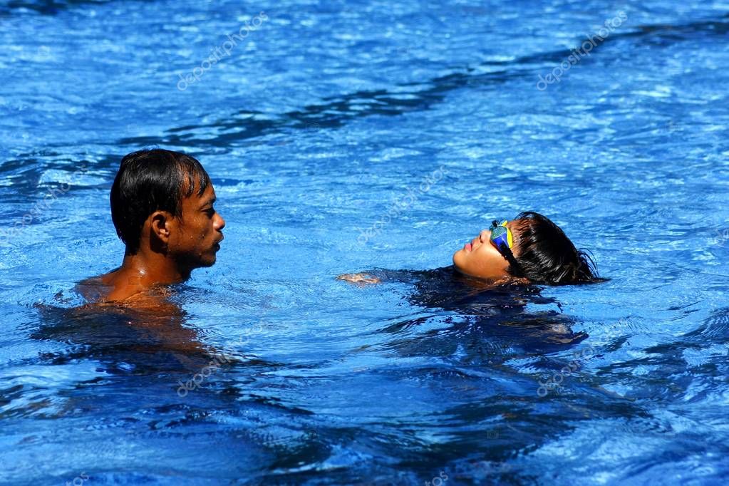 Un entrenador de natación le enseña a un niño cómo flotar o enhebrar el ...