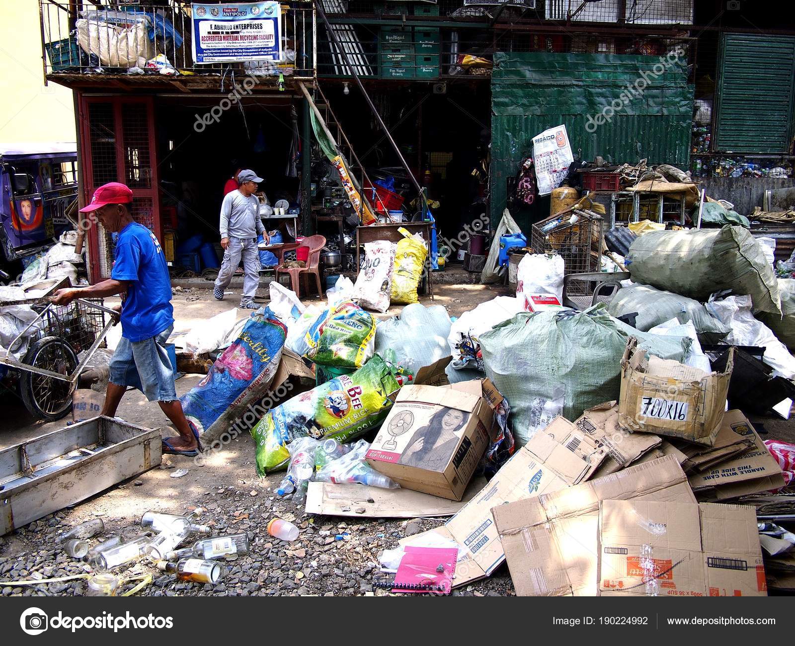 Workers of a junk shop or materials recovery facility sort through all ...
