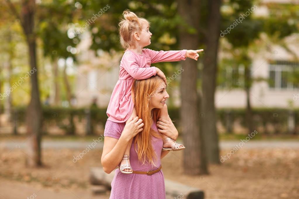 Una pequeña tabla camina con mamá en el parque. 2024