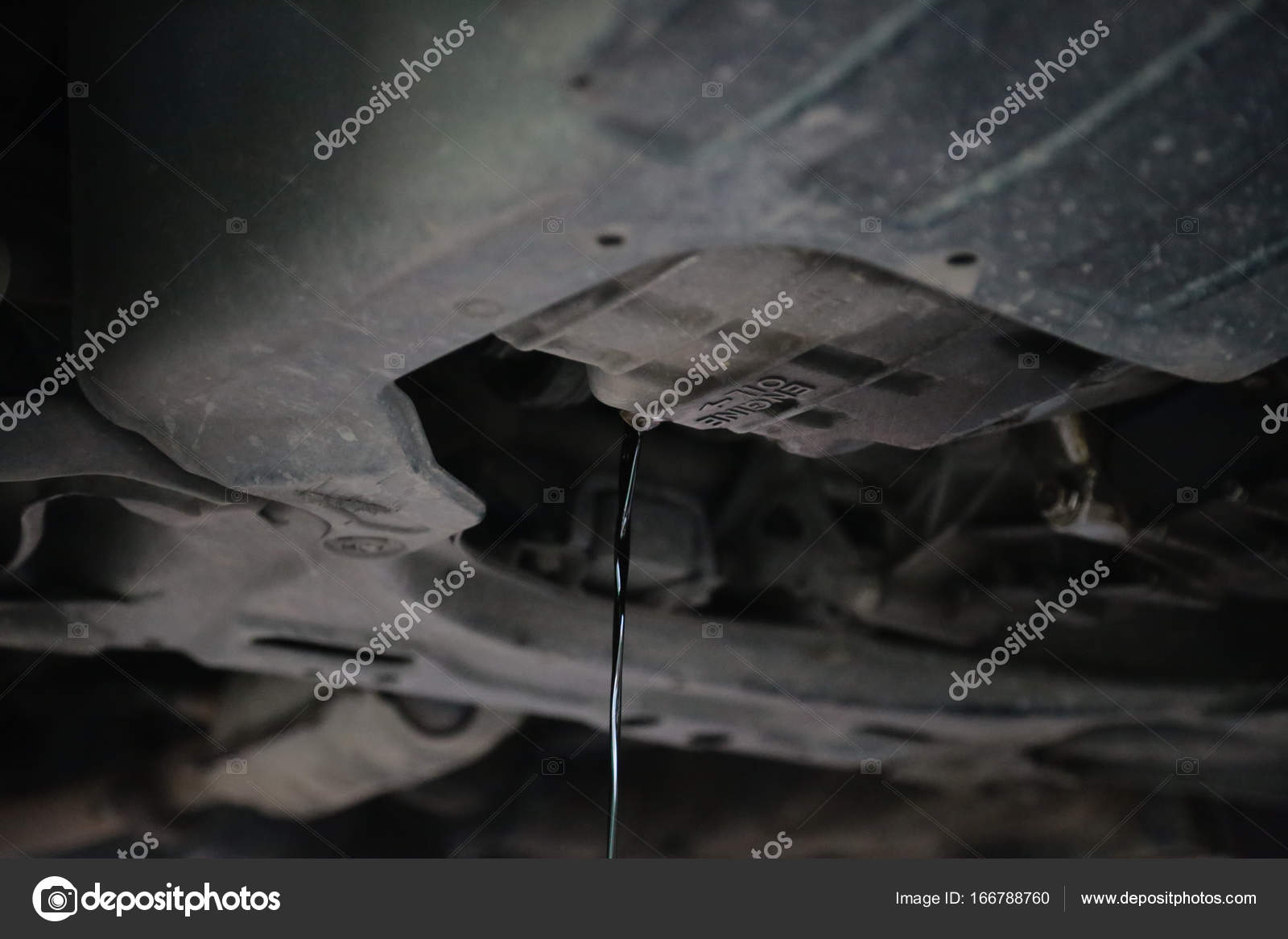 Old and dirty engine oil being drained from underneath a car during an ...