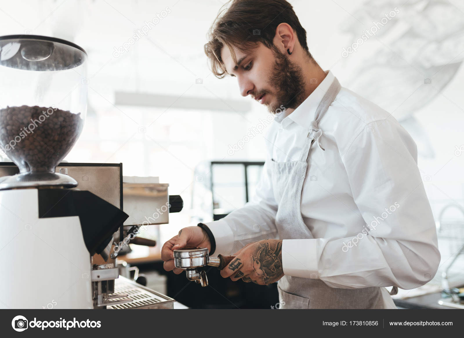 Portrait of young man working with coffee machine at the bar counter in ...
