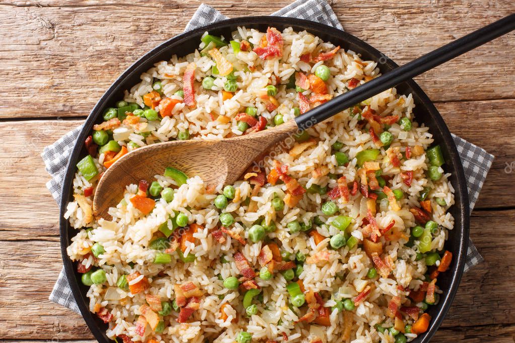 Arroz sabroso cocido con verduras y tocino de cerca en un plato. 2022