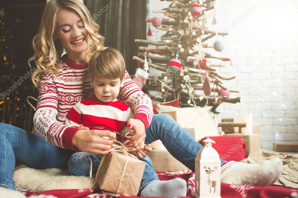 Retrato de feliz madre e hijo en el fondo del árbol de Navidad en la habitación de año nuevo. La ...