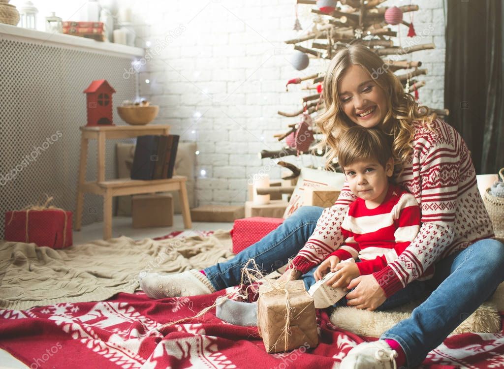 Retrato de feliz madre e hijo en el fondo del árbol de Navidad en la habitación de año nuevo. La ...