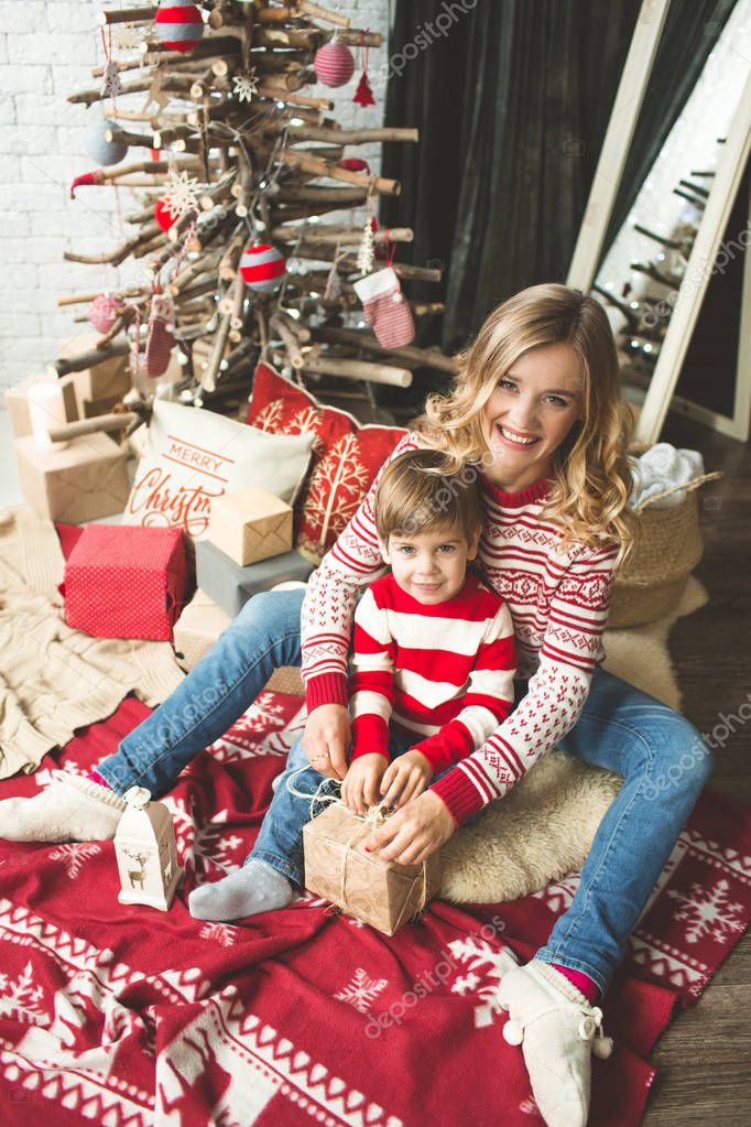 Retrato de feliz madre e hijo en el fondo del árbol de Navidad en la habitación de año nuevo. La ...