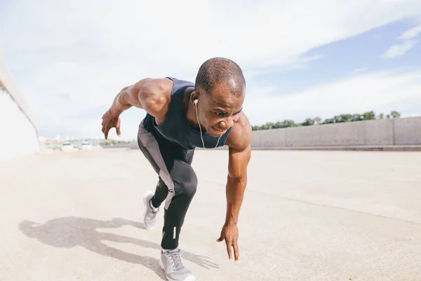 Athlete man in running start pose on the city street. Sport tight ...
